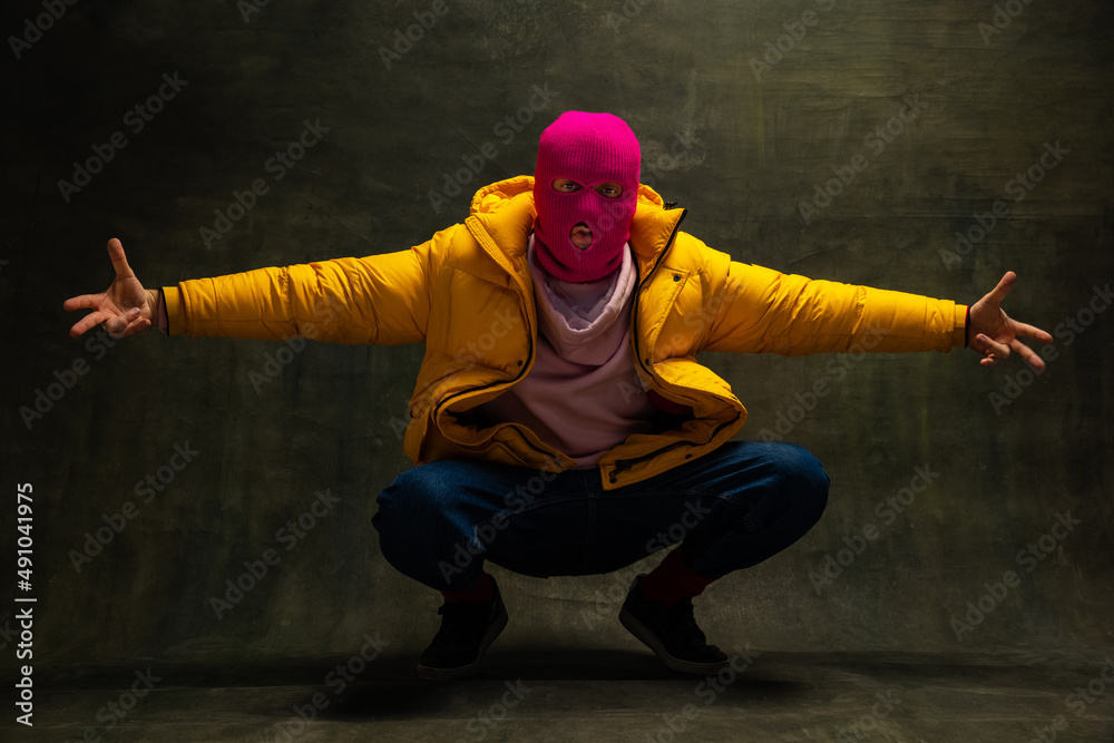 Studio shot of young anonymous man wearing pink balaclava and yellow ...