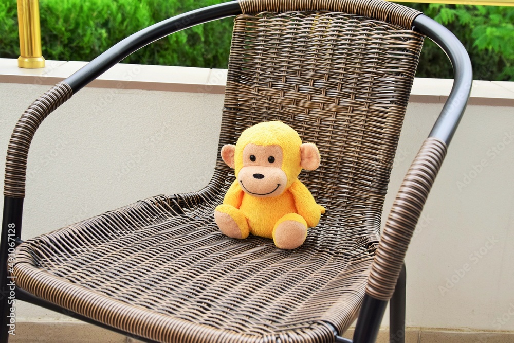 Soft toy monkey sits on a wicker chair Stock Photo | Adobe Stock