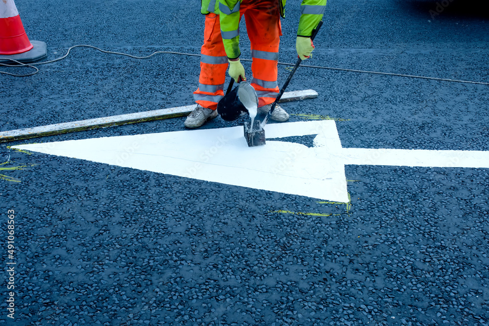 Roadworker painting road marking on the new-laid asphalt surface during ...