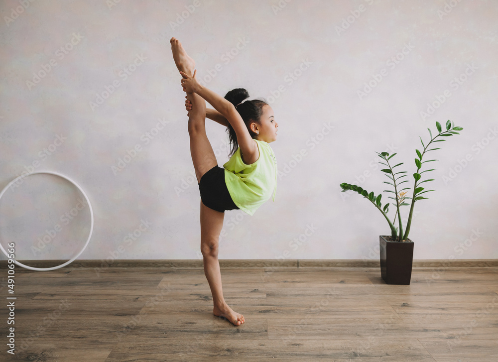 The little girl in raised her leg. Little gymnast trains at home. child ...