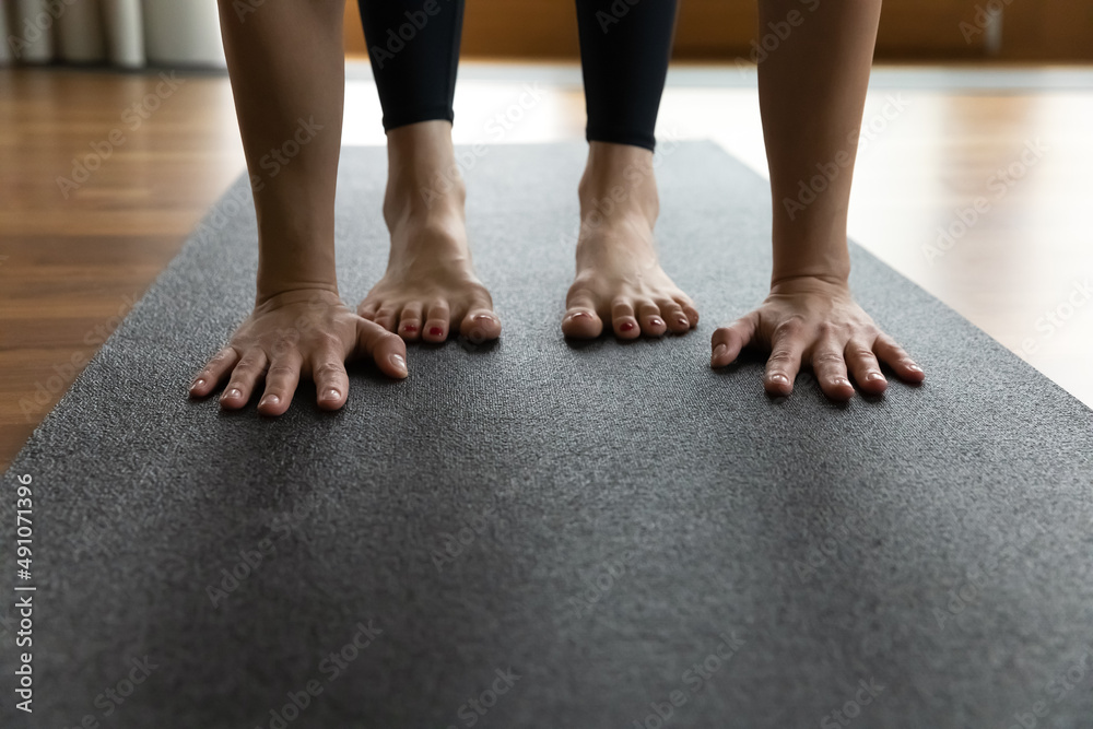 Plakát Woman standing barefoot on black rubber mat performs Standing ...