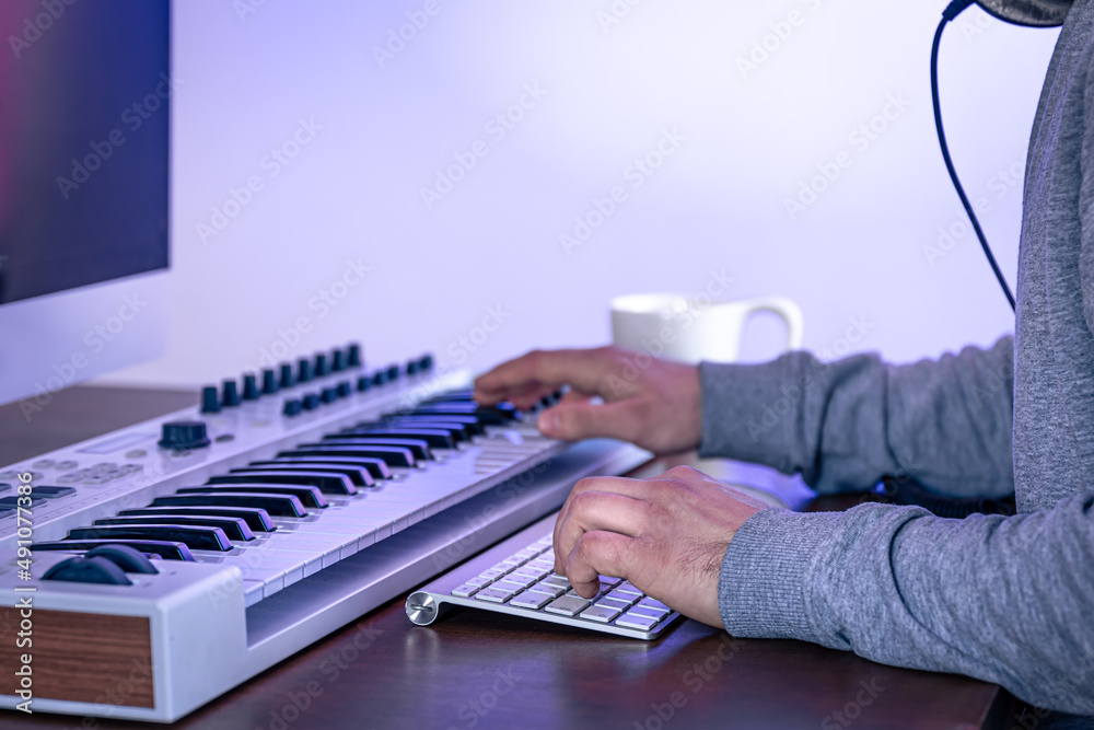 Male musician creates music using computer and keyboard, musician ...