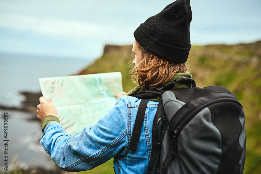 Finding my way through nature. Shot of a young man looking at a map for ...