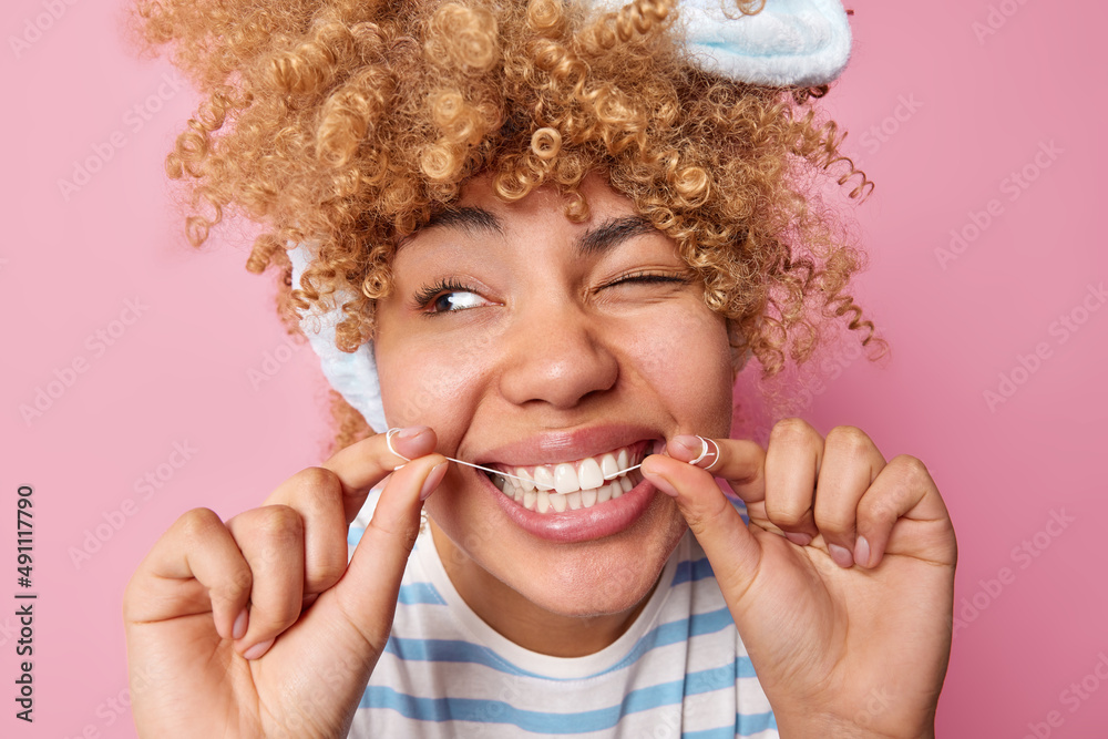 Tooth care routine concept. Young woman with curly hair uses dental ...