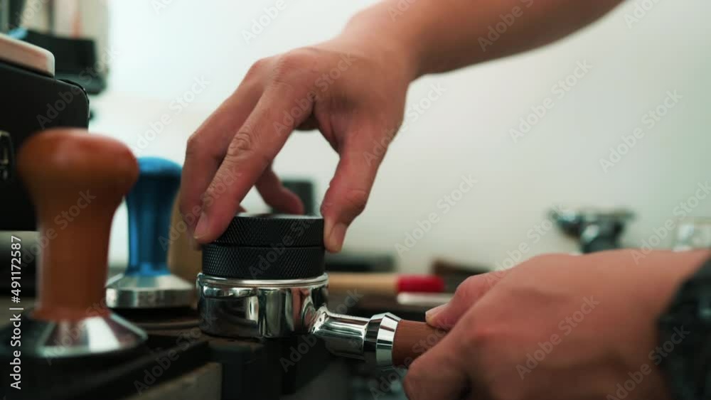 4K A barista presses ground coffee powder in a port a filter to make a ...