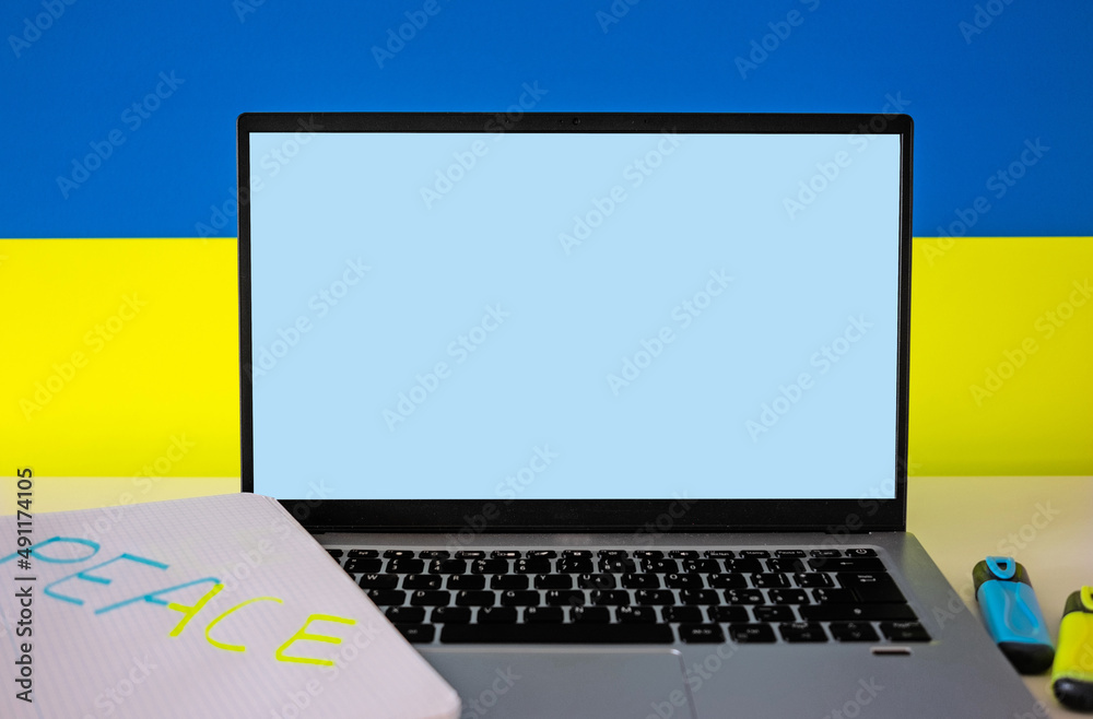 Flag of Ukraine on the background and wide digital screen of laptop for ...