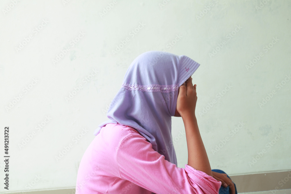 Girl sitting alone with sad feeling on white background. Child with ...