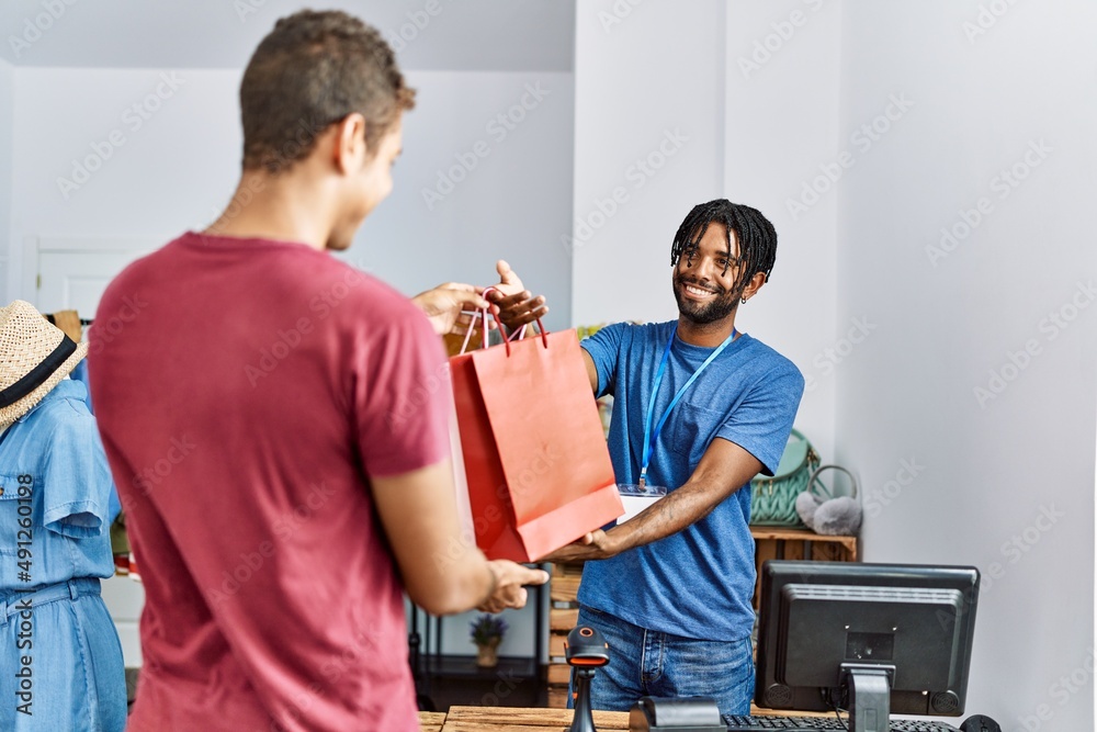 Two men shopkeeper and customer holding shopping bags at clothing store ...