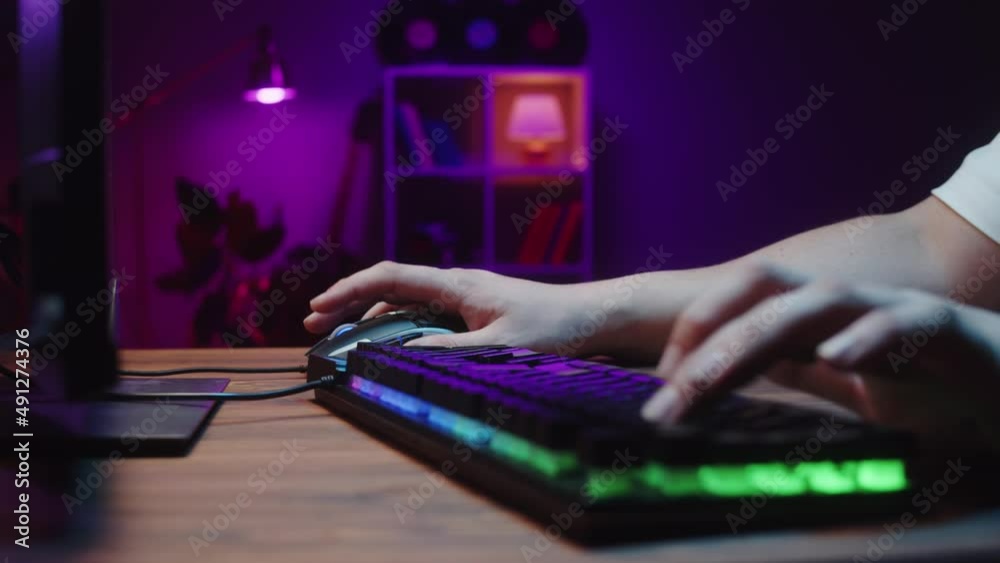 Gamer typing on backlight keyboard close-up, man playing video game ...