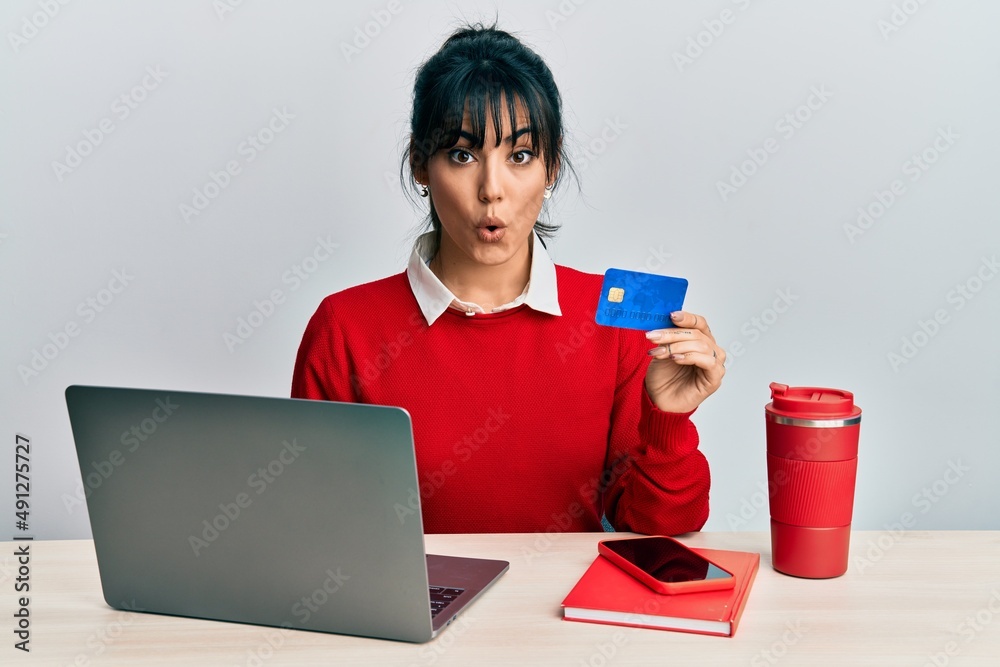 Young brunette woman with bangs working at the office using laptop and ...