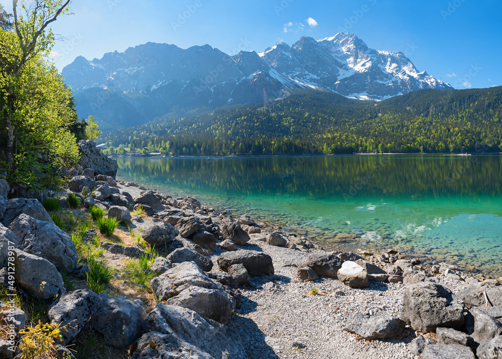 rocky bathing beach at lake shore Eibsee, view to Zugspitze mountain ...