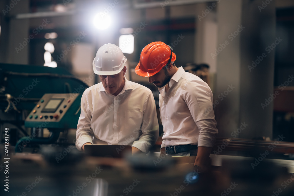 Factory worker man and engineer manager working together a metal sheet ...