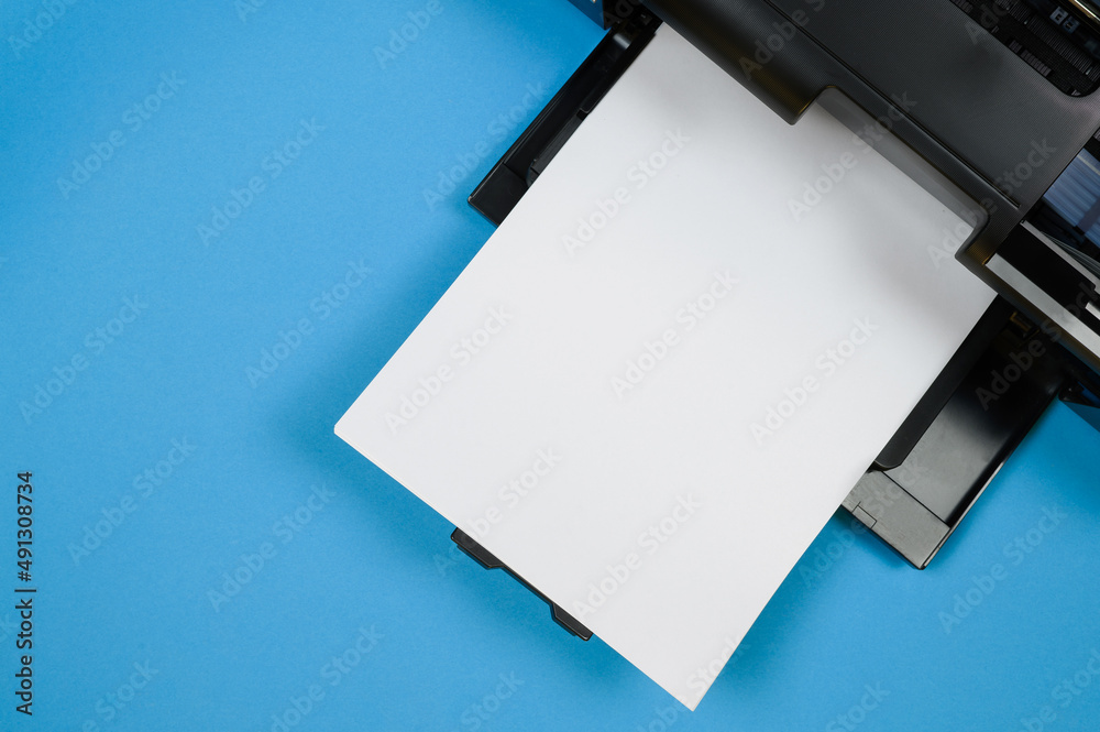Top view of the printer and a blank sheet of a4 paper on a blue ...