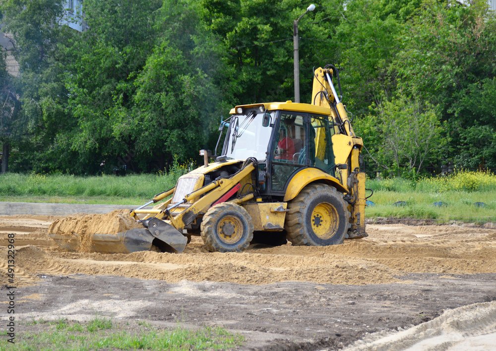 A backhoe pushing a pile of sand.This is a type of excavating equipment ...