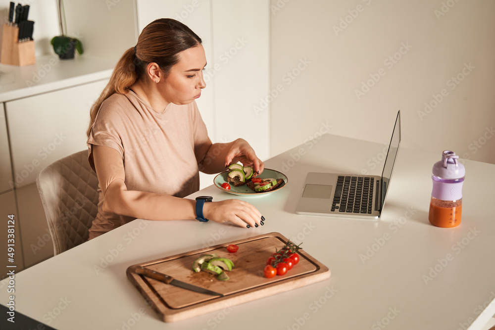 Woman with artificial limb eating sandwiches at the table while ...
