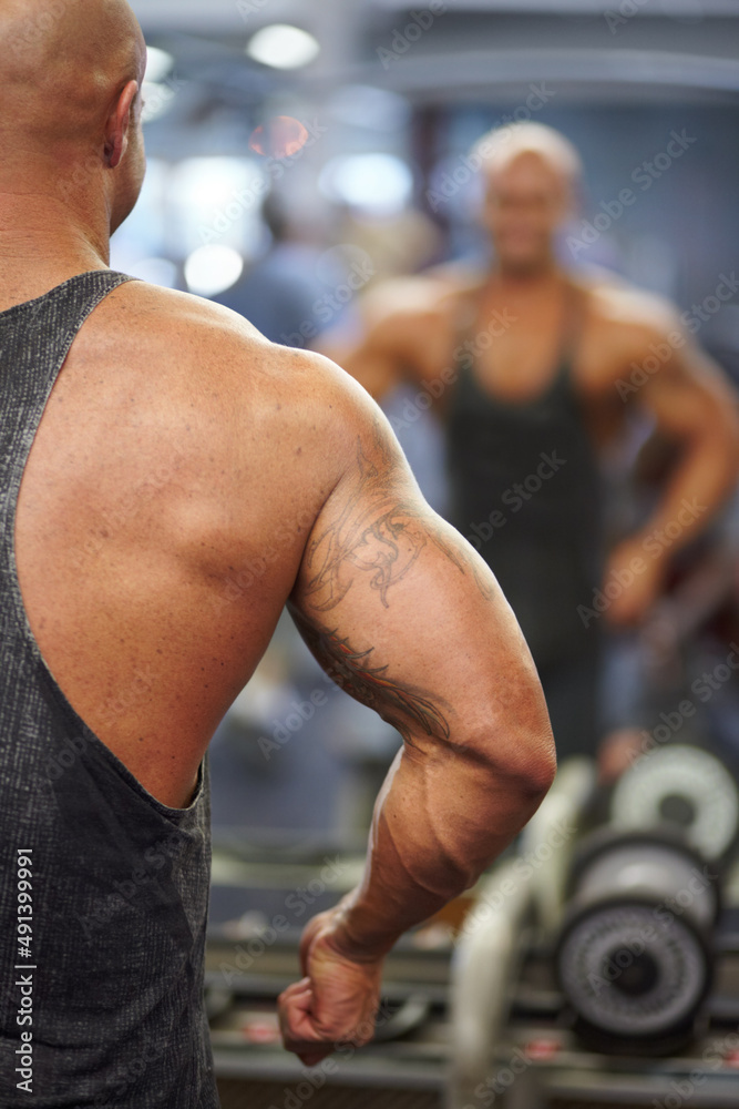 Admiring his physique. A muscular bodybuilder flexing his muscles while ...