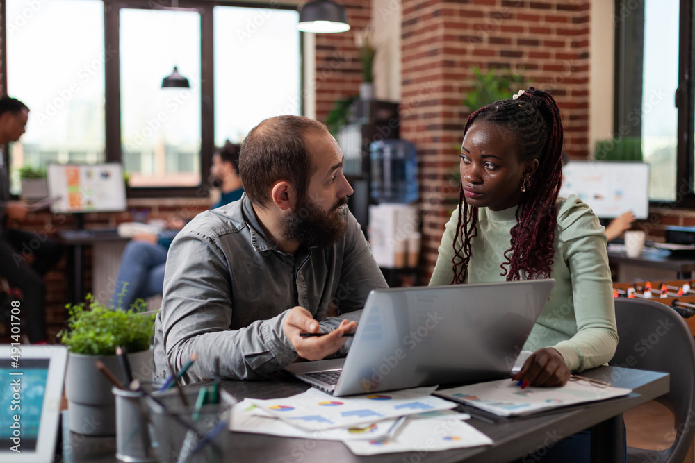 Diverse team analyzing marketing statistics on laptop computer ...