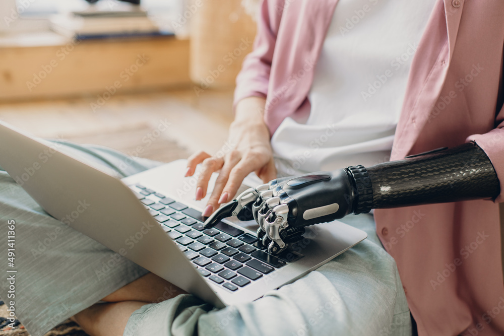 Crop shot of bionic black robotic hand typing on keyboard of laptop ...