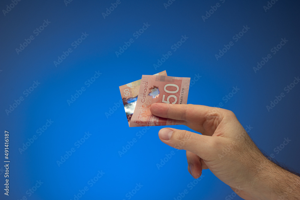 Paper banknote of 50 Canadian dollar bill held between fingers by ...