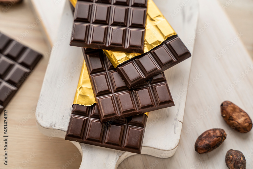 Chocolate bars with open gold cover. Stack of chocolate bars with cacao ...