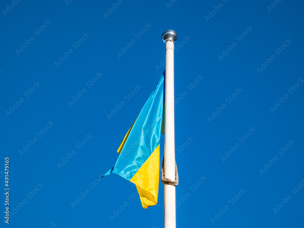 The blue and yellow Ukrainian flag flying in the sky on the flagpole in ...