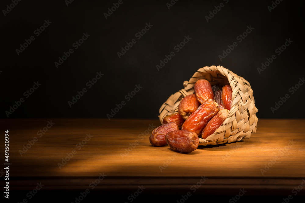 Ripen Arabian dates placed in a palm basket on a dark background ...