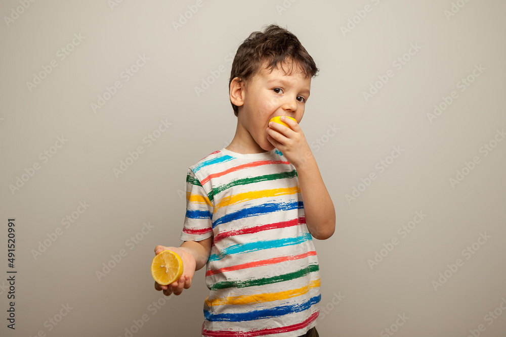 little boy eating lemon, sour taste, makes grimace, facial emotions ...