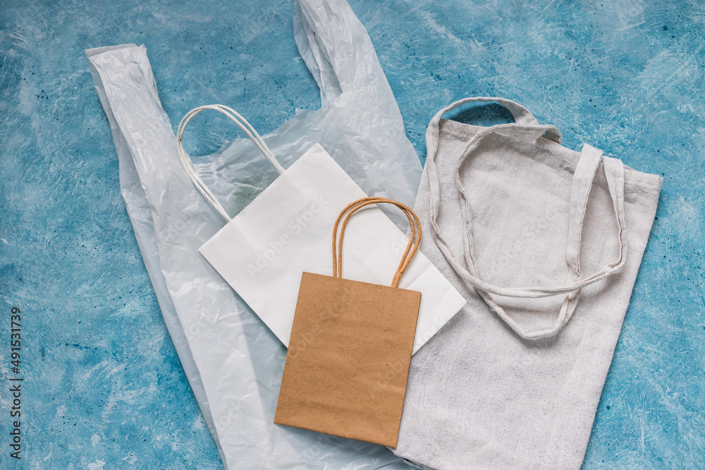 single use plastic bag next to paper and reusable canvas ones, plastic ...
