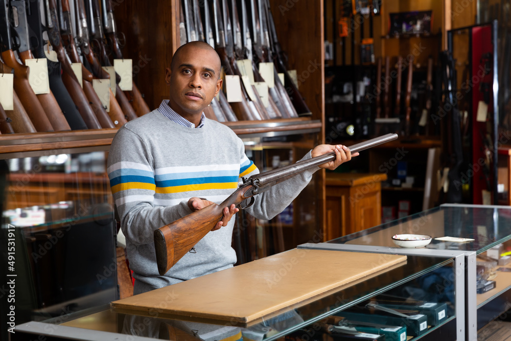 Latin american man owner of armory shop standing behind counter and ...