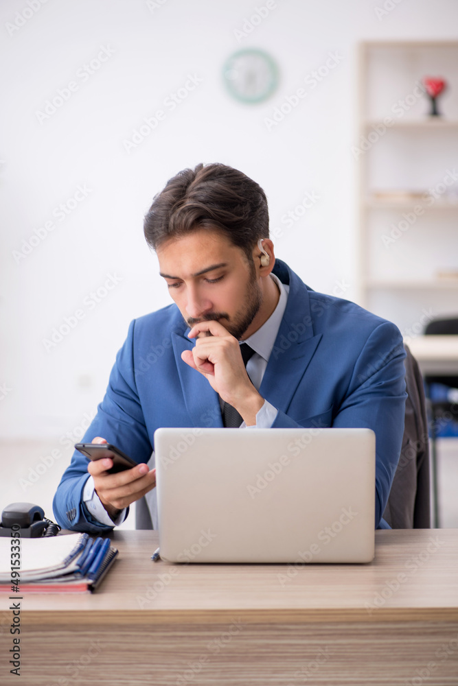 Deaf male employee using hearing aid at workplace Stock Photo | Adobe Stock
