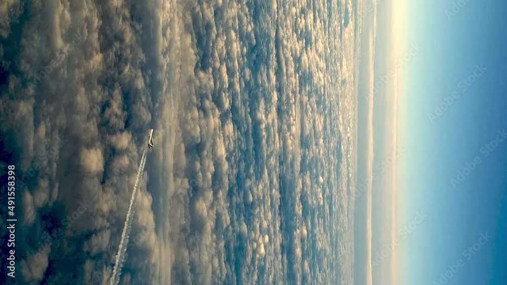 Flying airplane above clouds leaving condensation vapor air trail in ...