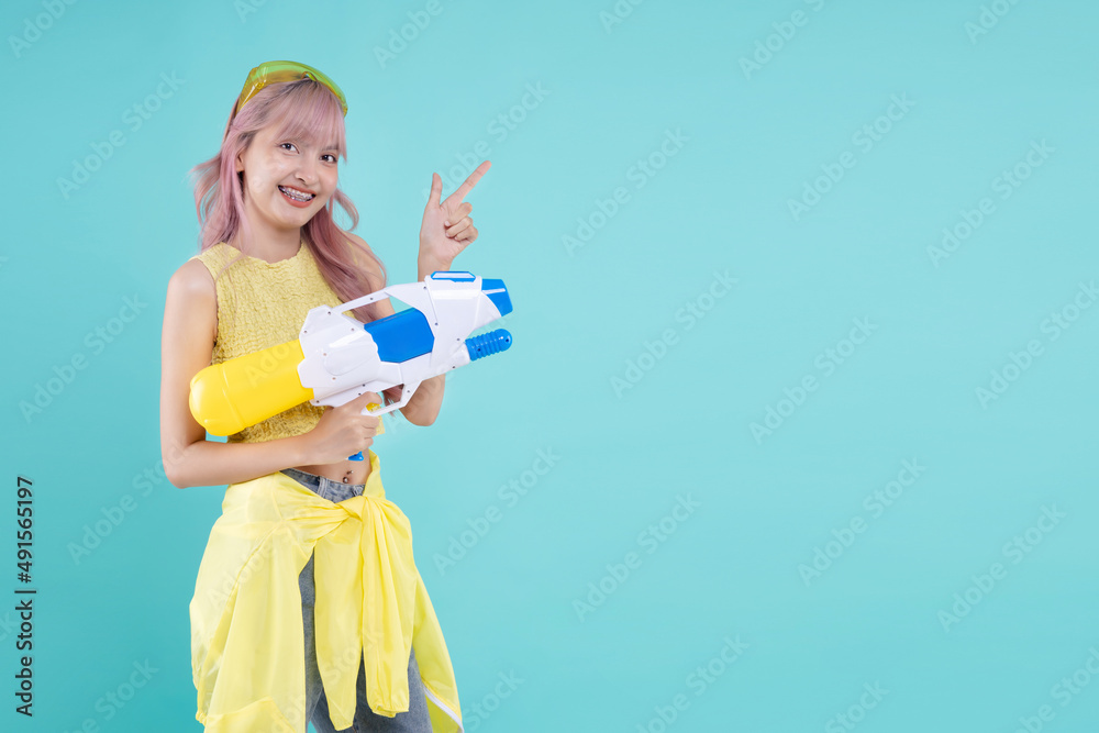 Happy Asian beautiful girl holding a water gun on pastel green mint ...