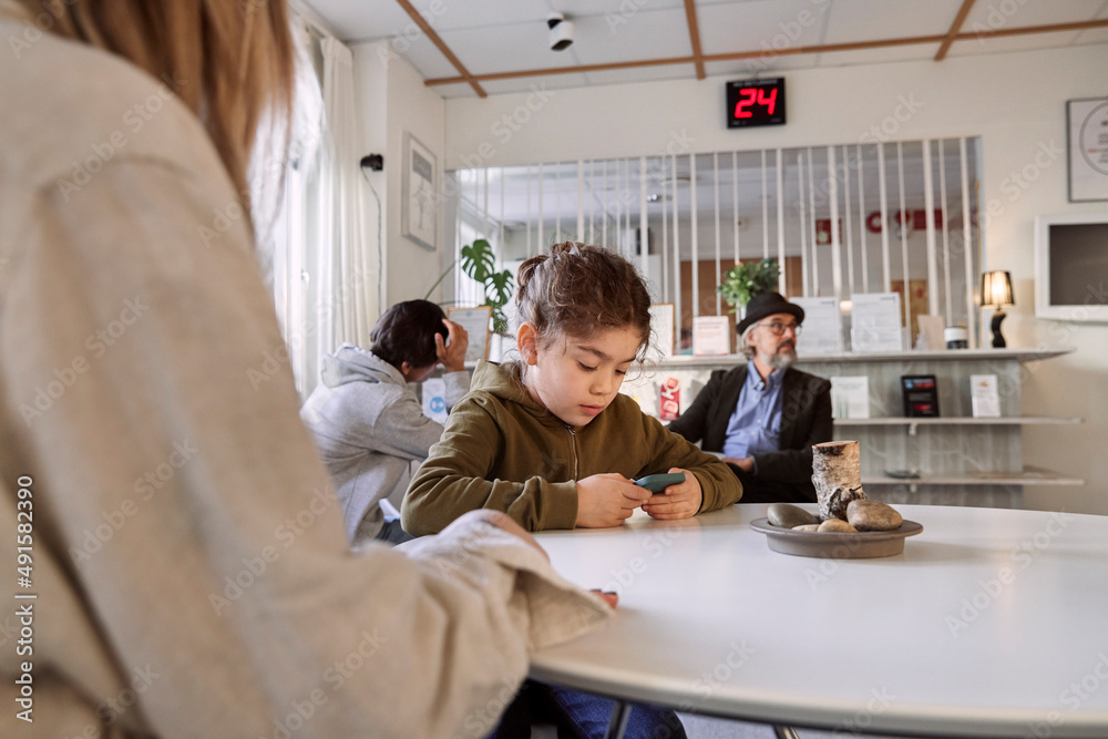Girl in waiting room using cell phone Stock Photo | Adobe Stock