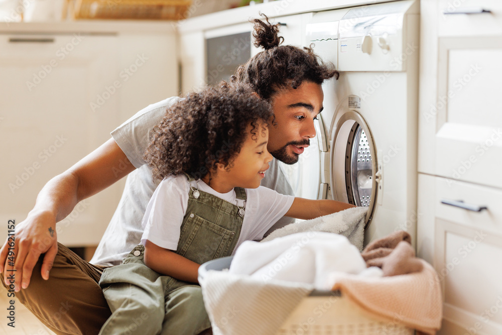 Son helping dad to load washing machine Stock Photo | Adobe Stock