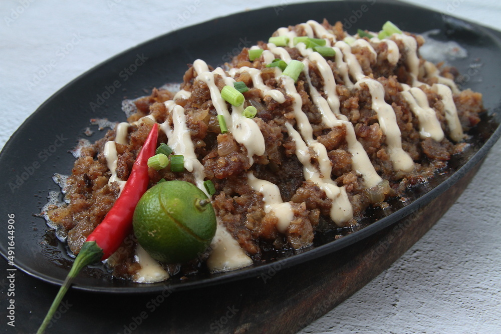Freshly made Filipino food called Pork Sisig or chopped pork served in ...