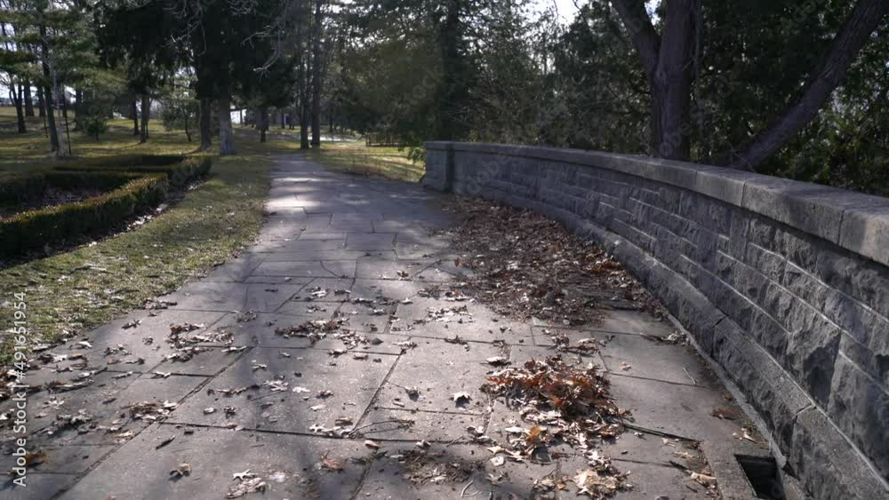Leaves blowing in strong wind during fall on walkway in park on pathway ...
