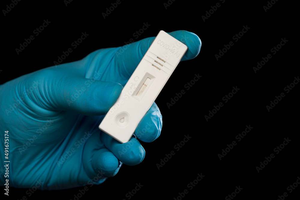 Close-up of hand in medical gloves handling showing result of antigen ...
