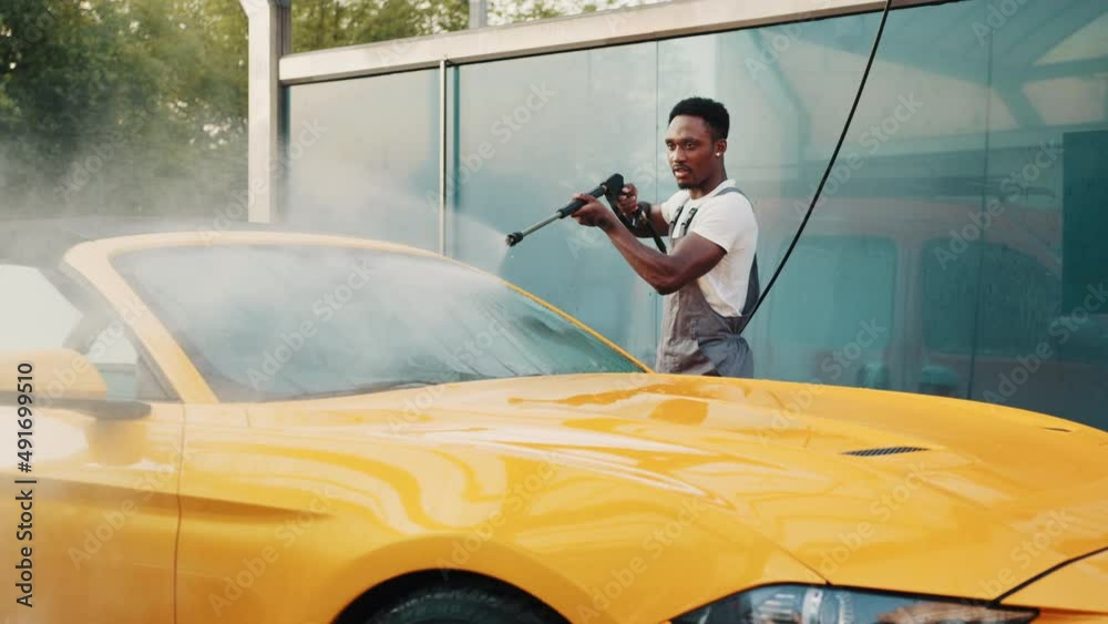 Vidéo Stock Manual car wash. Handsome African young man washing his ...