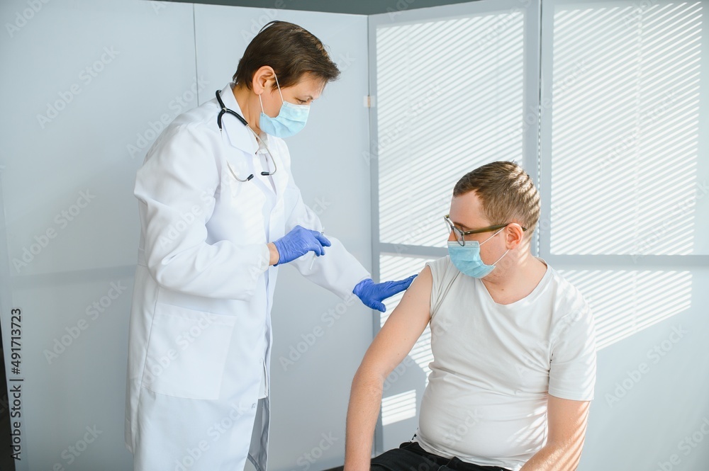 Close up of a Doctor making a vaccination in the shoulder of patient ...