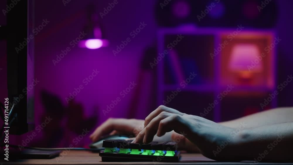 Gamer typing on backlight keyboard close-up, man playing video game ...