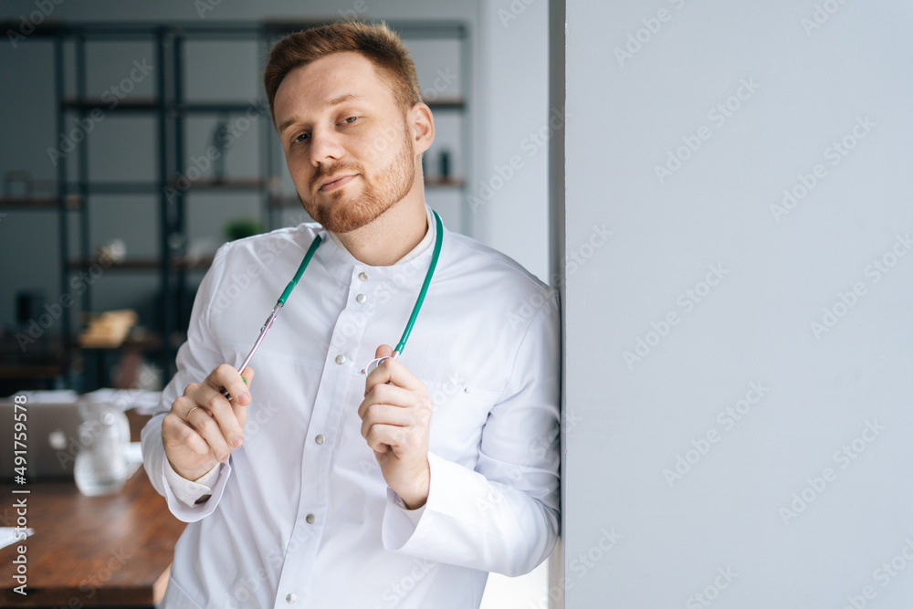 Portrait of handsome male doctor wearing white medical uniform standing ...