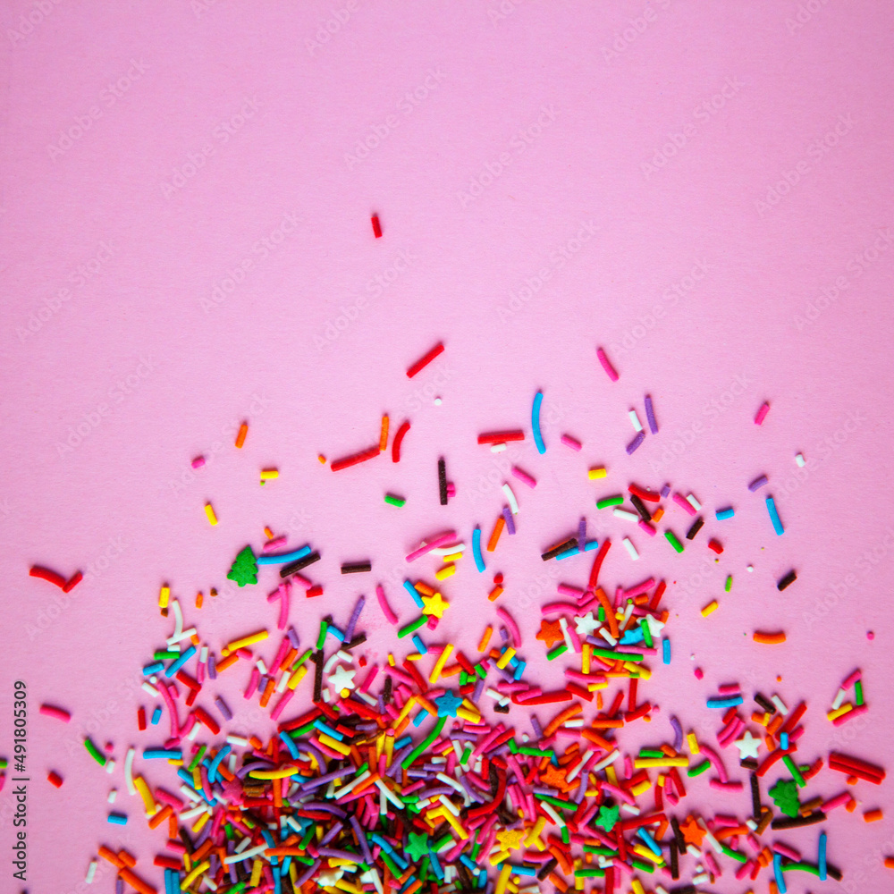 Colorful sprinkles scattered on pink background Stock Photo | Adobe Stock