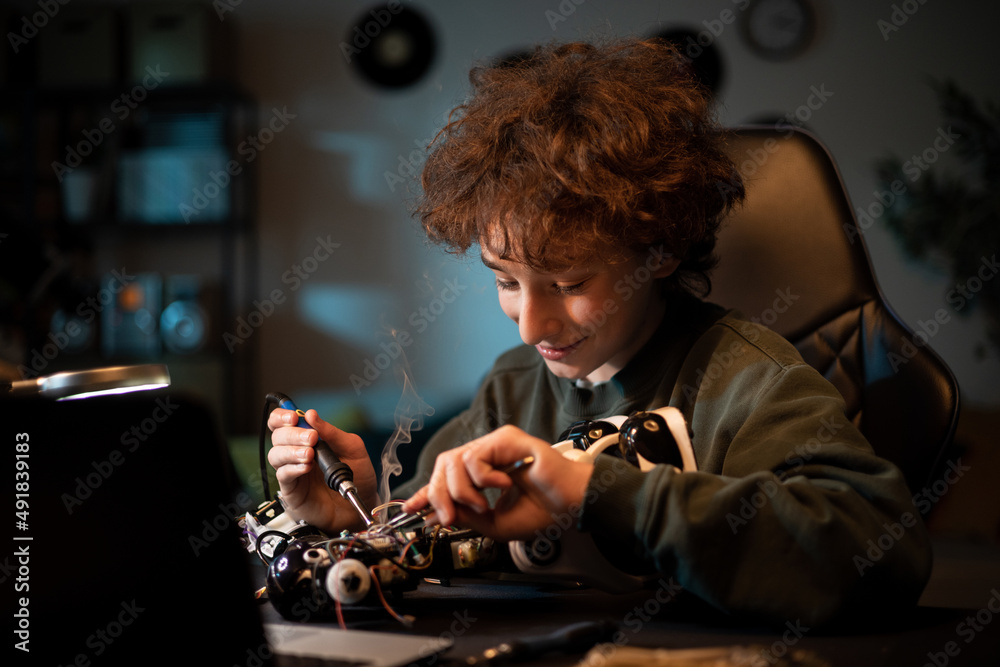 Foto de A smiling boy is learning electronics and soldering wires and ...