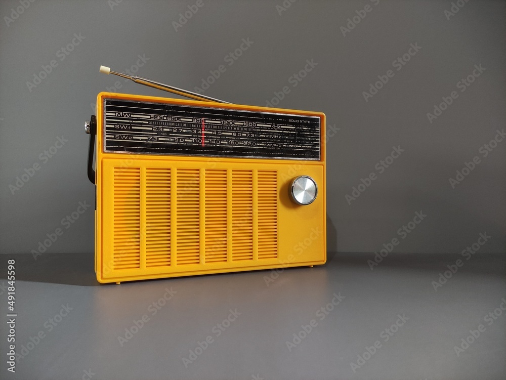 Vintage yellow transistor radio, dark grey background, listen music ...