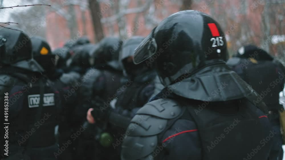Riot police officers marching among other policeman and protesting ...