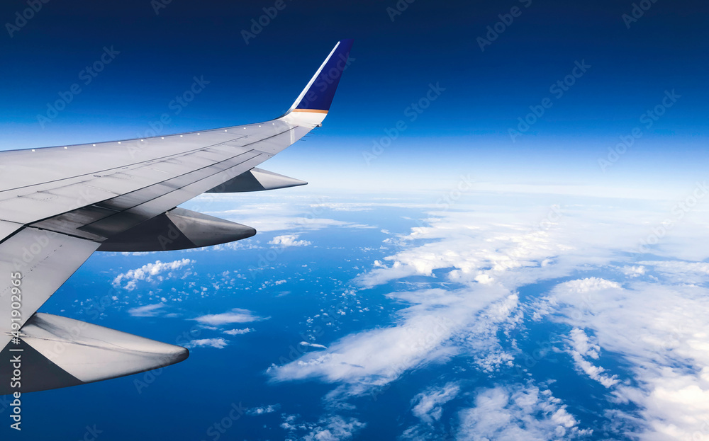 Sky view from inside the plane. The wing of the plane and the sky can be seen from inside the ...