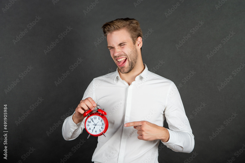 Happy crazy guy sticking tongue while pointing finger at alarm clock ...