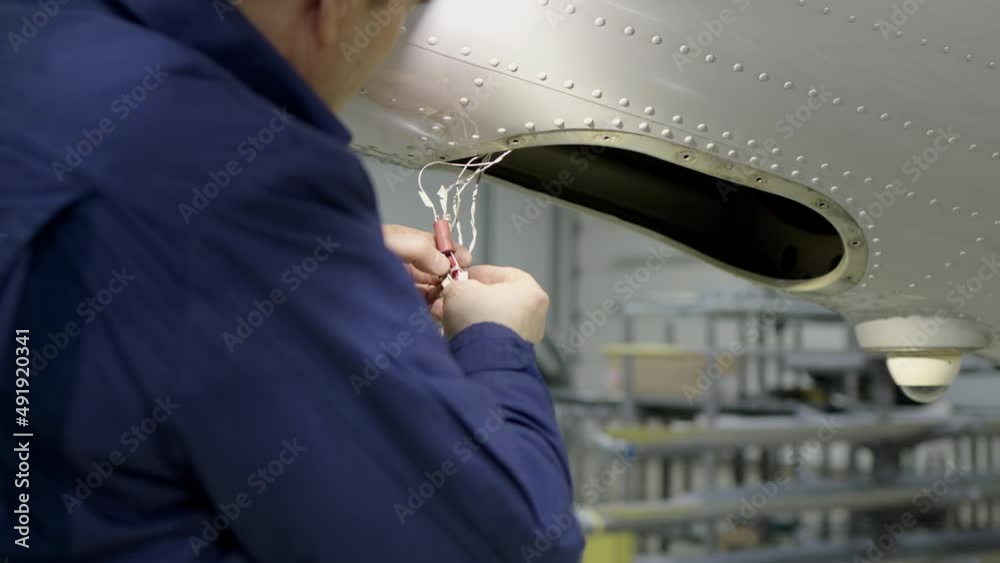 unrecognizable mechanic in blue overalls is fixing electrics on ...
