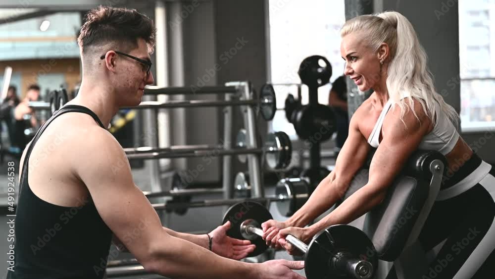 A male bodybuilder and an athletic woman assist each other with a ...