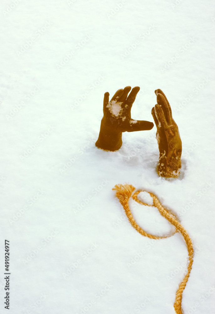 Buried in snow with gloved hands reaching out for lifeline rope a ...